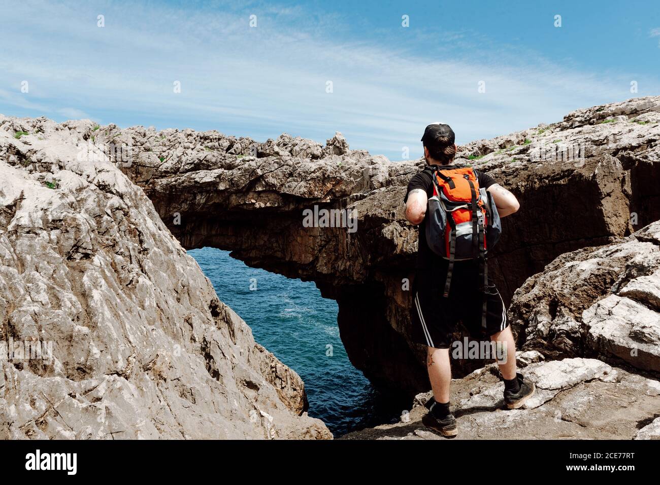Back view of anonymous male traveler exploring rough cliffs with uneven ...