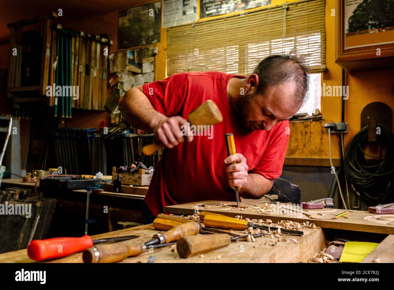 Talented craftsman standing at workbench and using chisel for wood ...