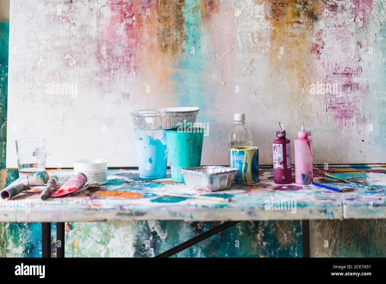 Plastic bottles with colorful paints and empty containers near artist ...