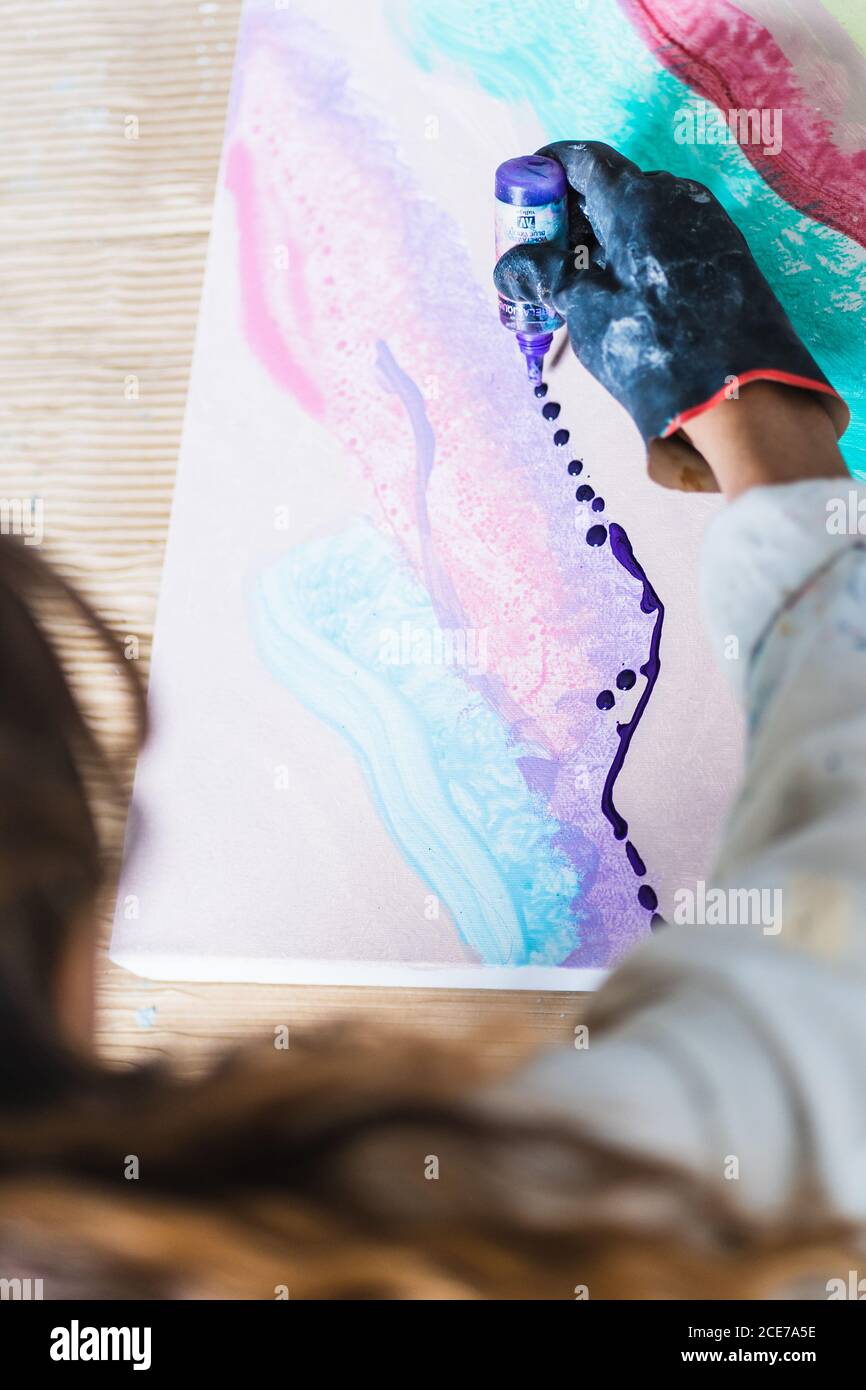 Cheerful barefoot female artist in dirty robe and gloves lying on ...