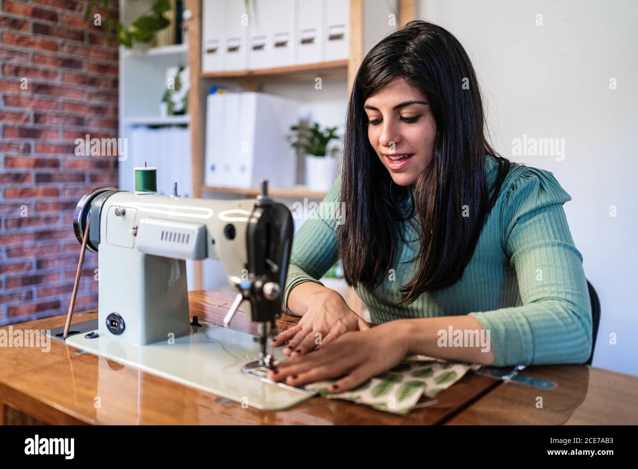 CraftsWoman using modern sewing machine while creating soft fabric ...