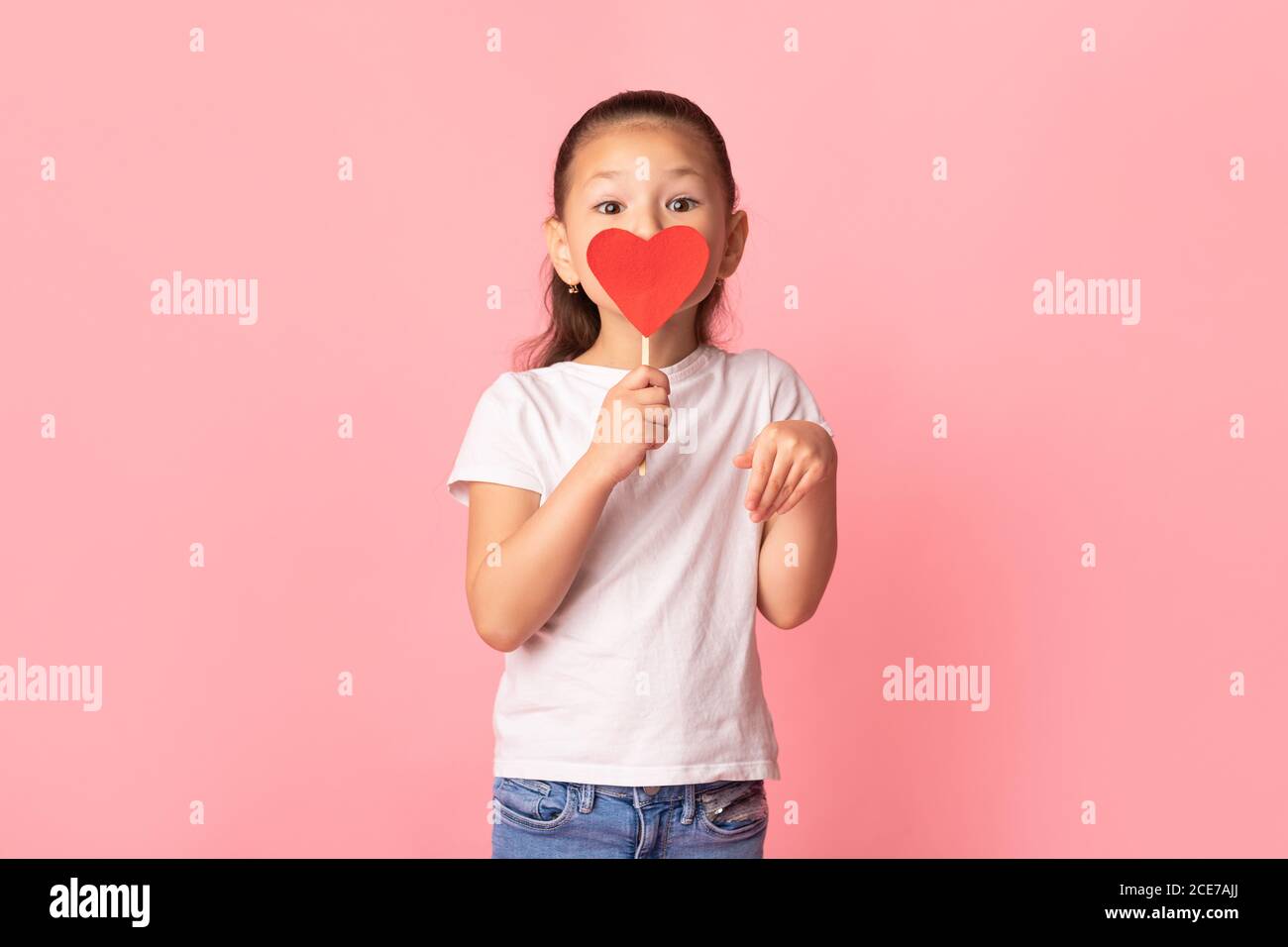 Asian little girl holding paper heart near mouth Stock Photo - Alamy