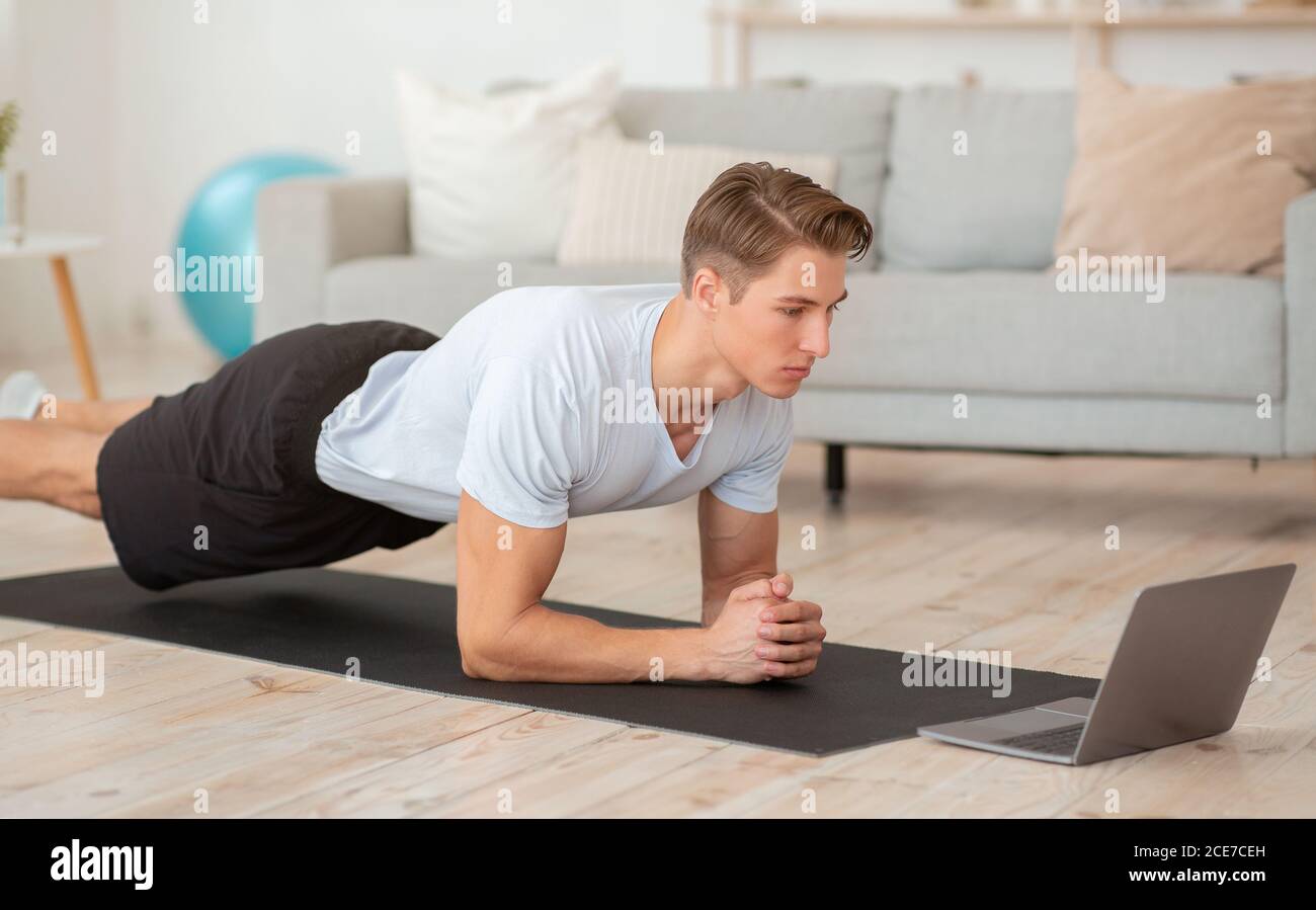 Fitness training, static exercises. Muscular man with laptop makes ...