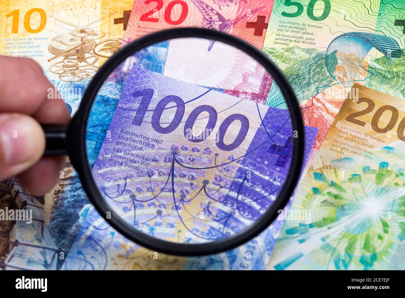 Swiss money in a magnifying glass a business background Stock Photo - Alamy