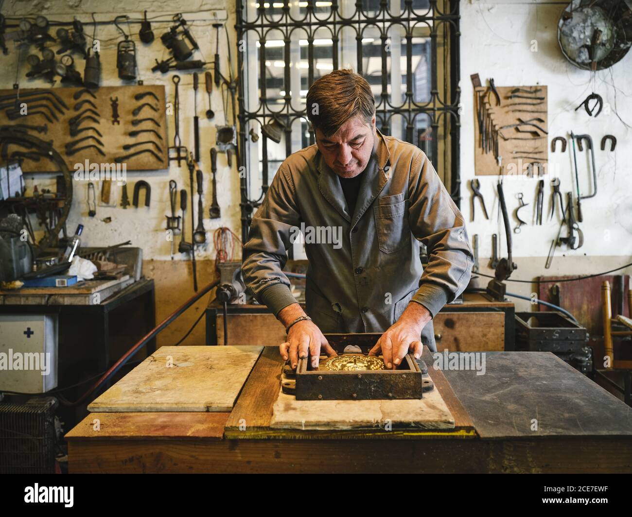 Crop of goldsmith placing metal pattern into molding box during casting ...