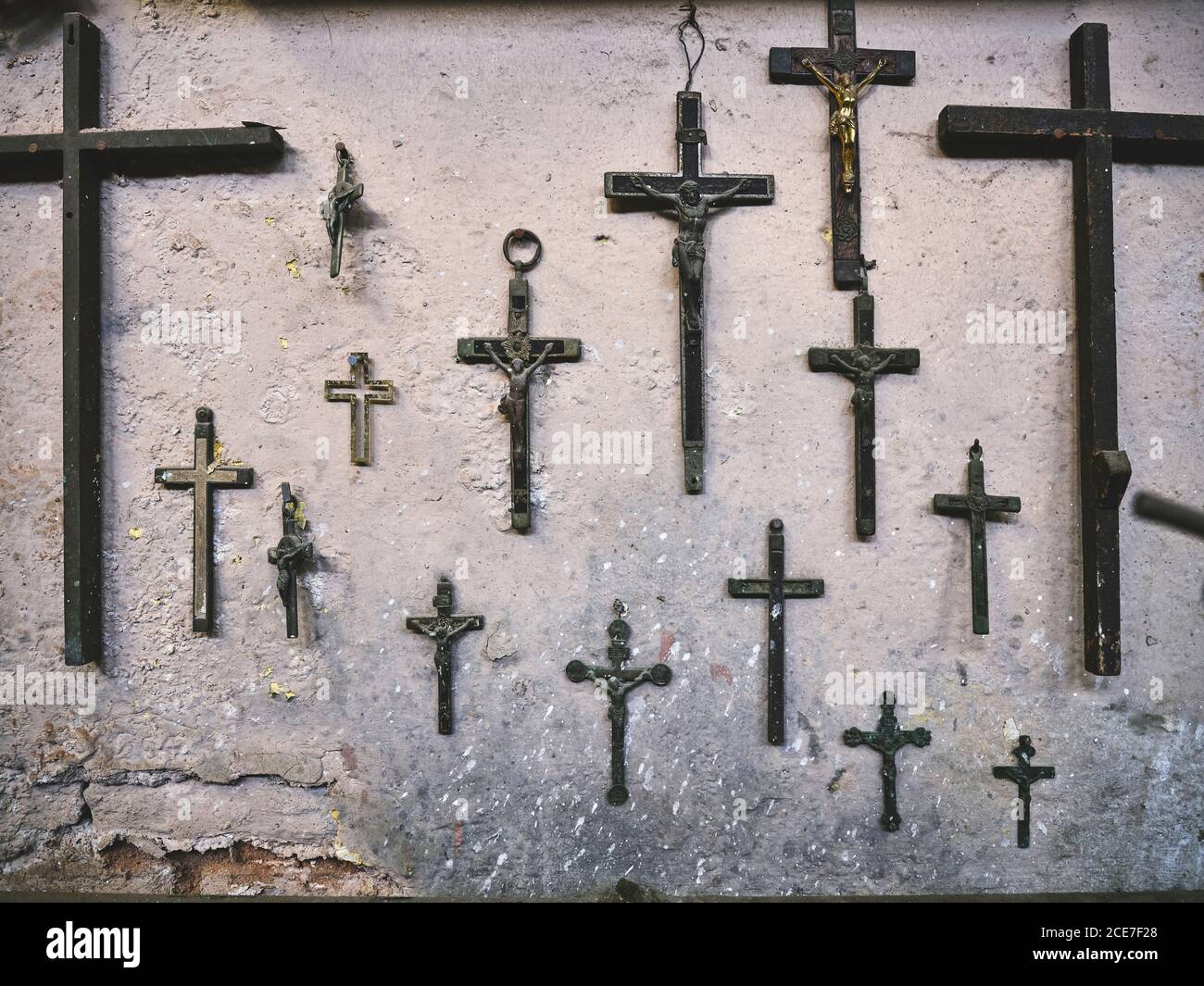 Set of metal crosses with crucifix hanging on weathered cement wall in ...