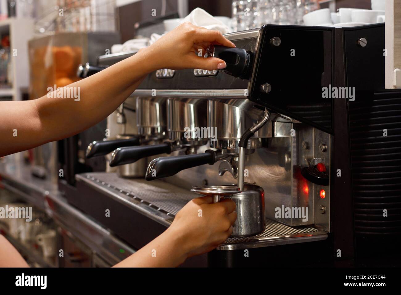Side view of unrecognizable female barista using coffee machine and ...