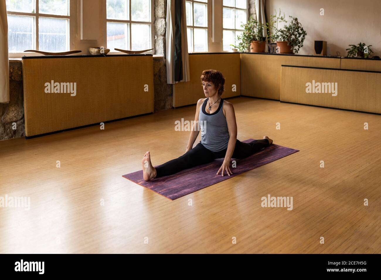 Full body of focused female yogi in sportswear performing monkey pose ...