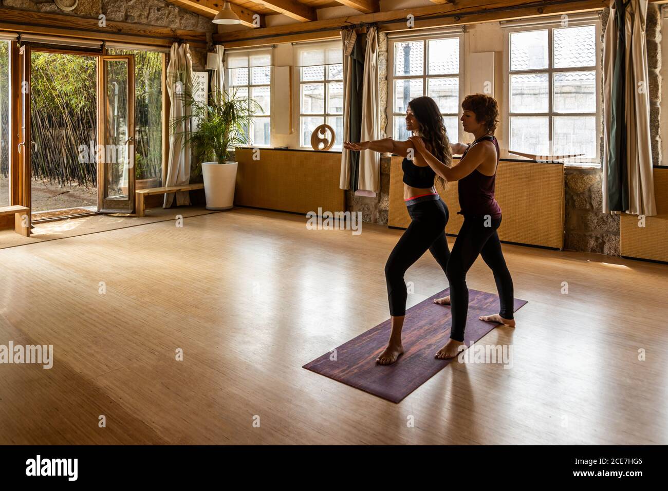 Flexible Woman standing in Warrior pose and practicing yoga with help ...