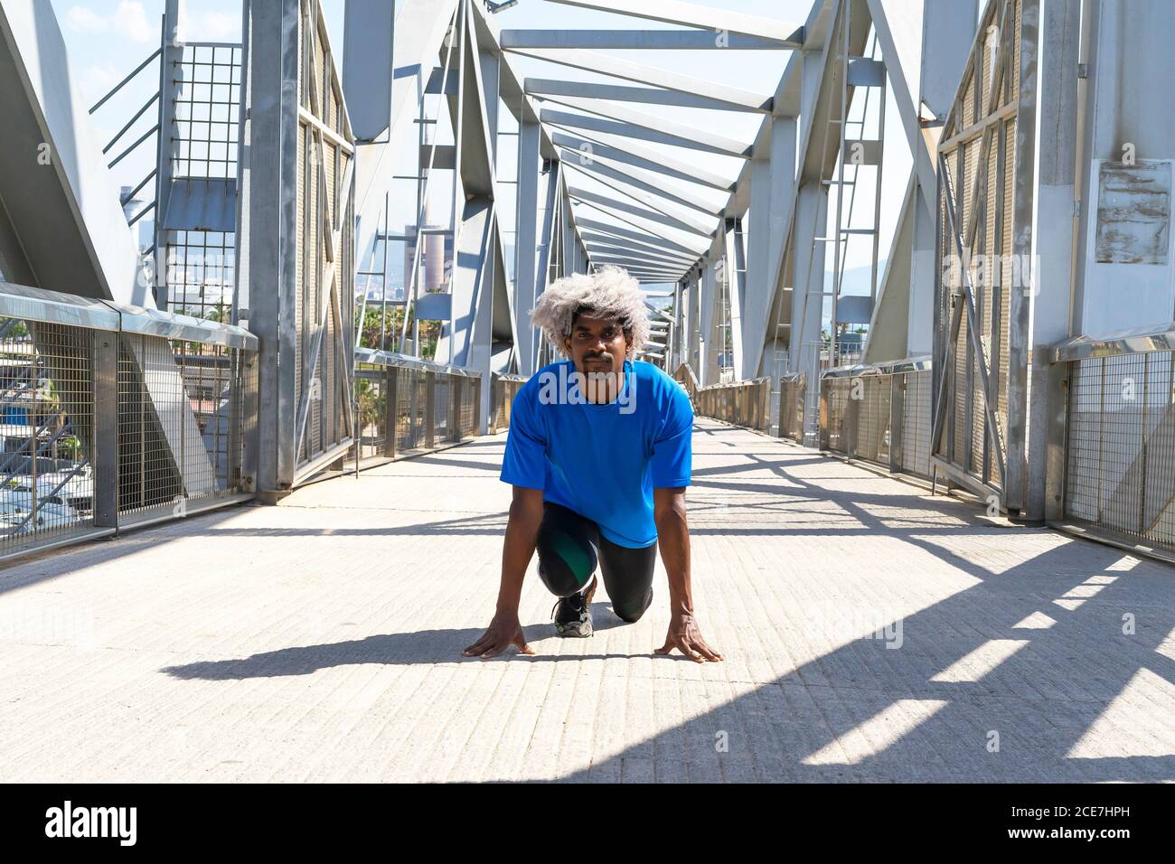 Black athlete with blond hair taking crouch start position before ...