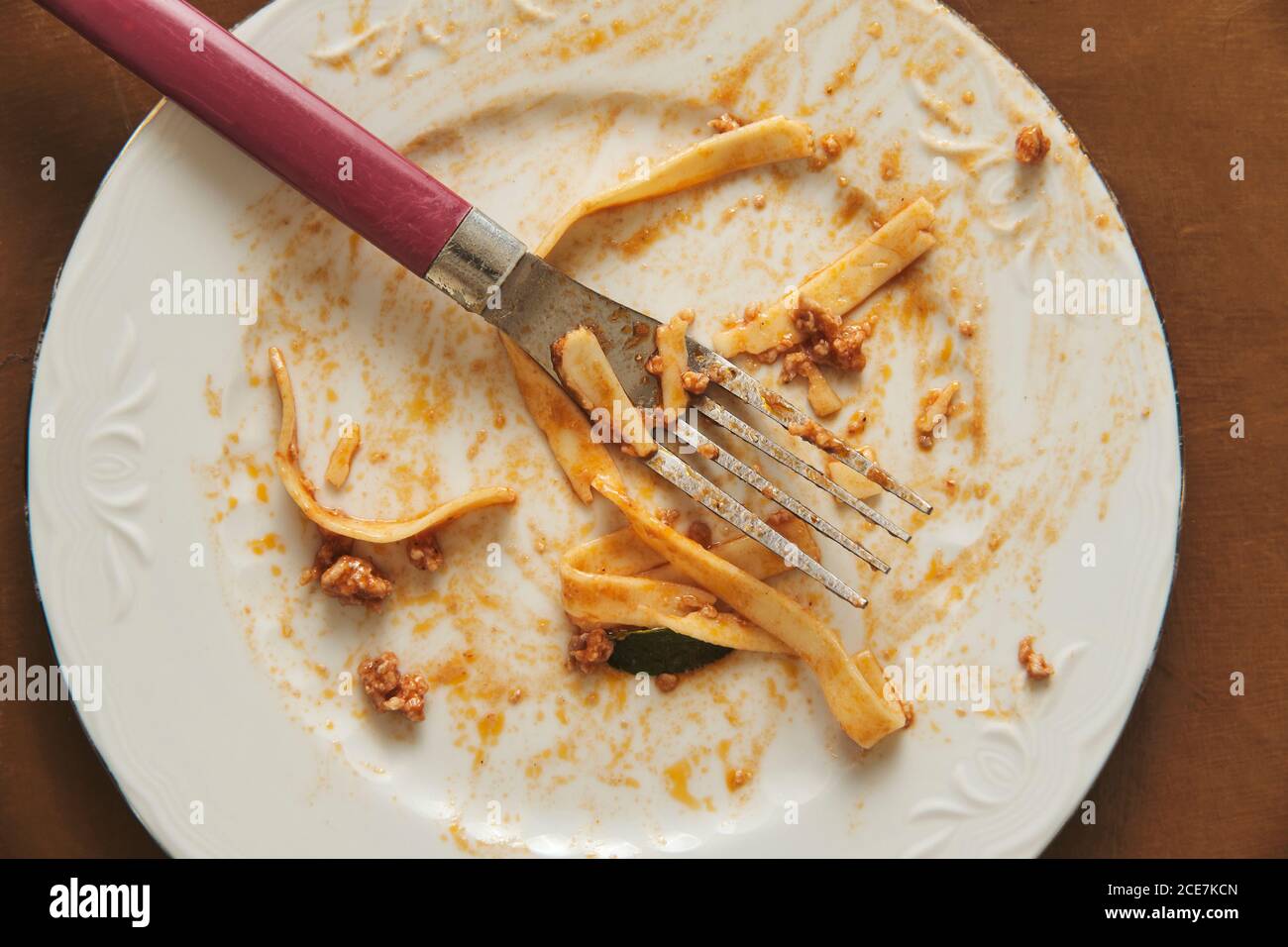 Top view of empty white plate and fork smeared with food after eating ...