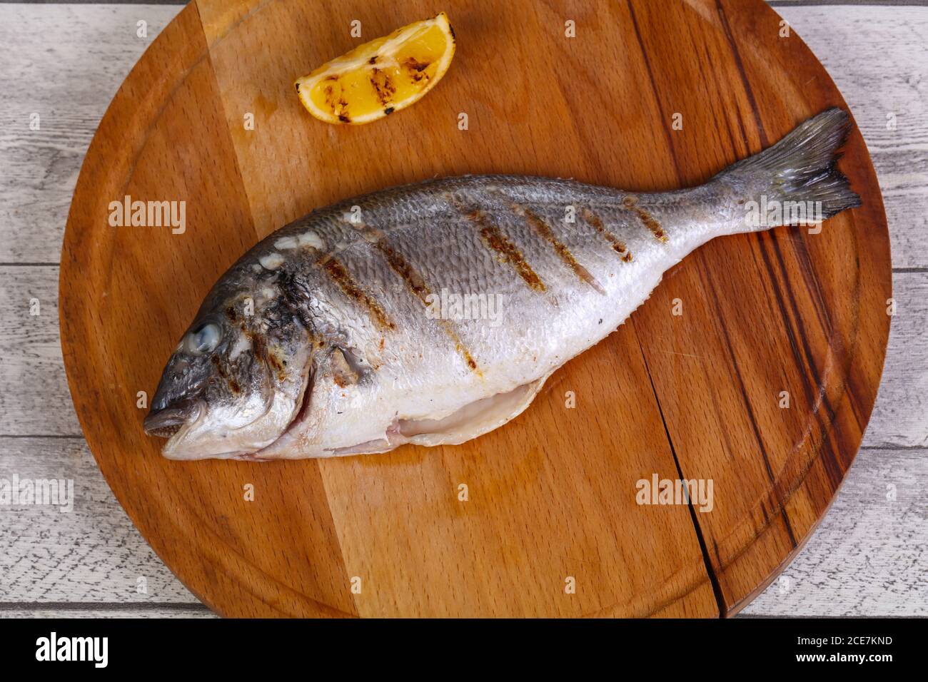 Grilled dorada with lemon over the wooden board Stock Photo - Alamy