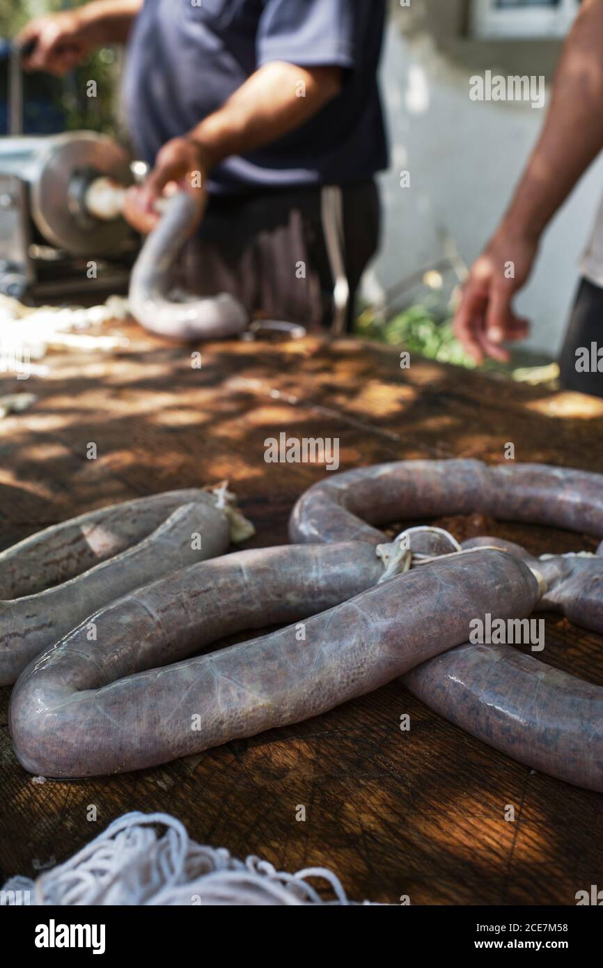 High angle of crop anonymous man filling natural sausage casing with ...