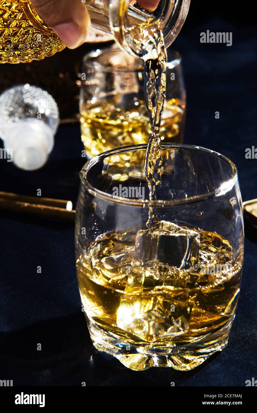 anonymous person serving whiskey in a glass Stock Photo - Alamy