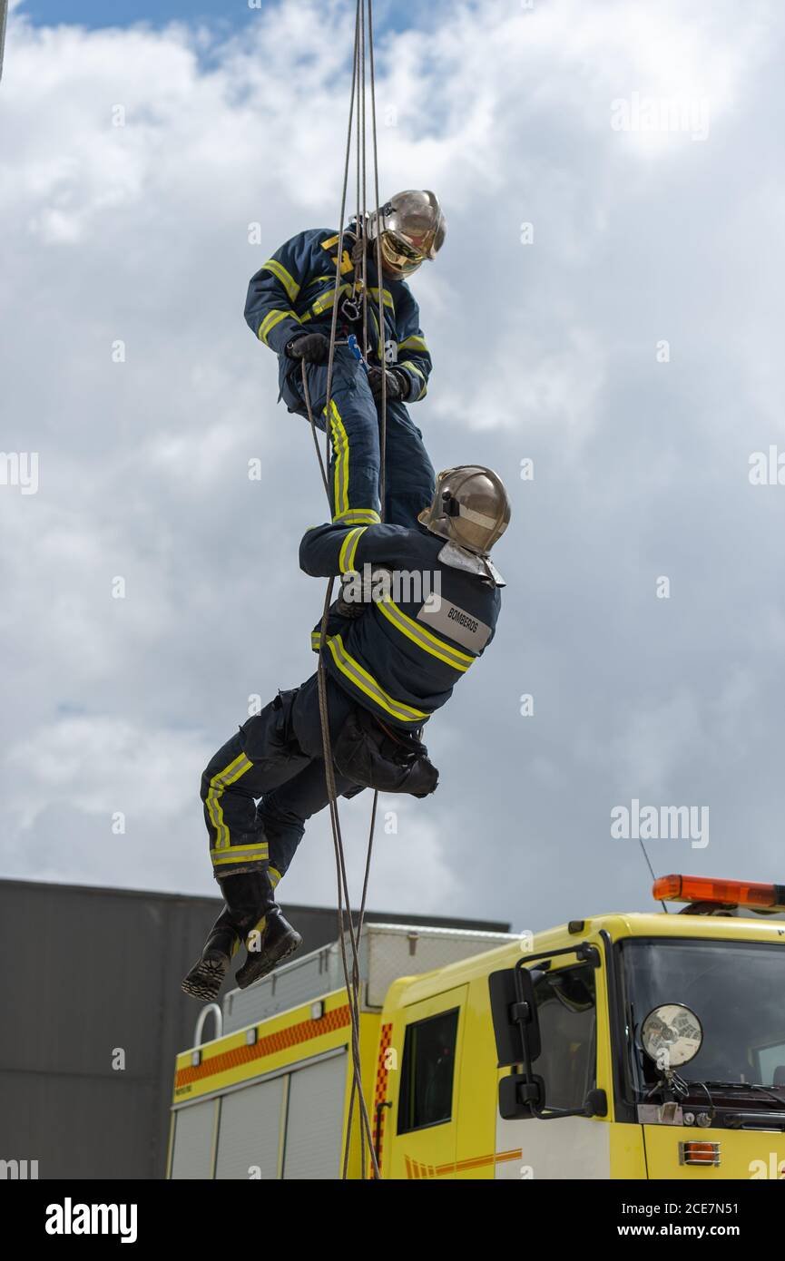 From below of firefighters in protective equipment climbing ropes near ...