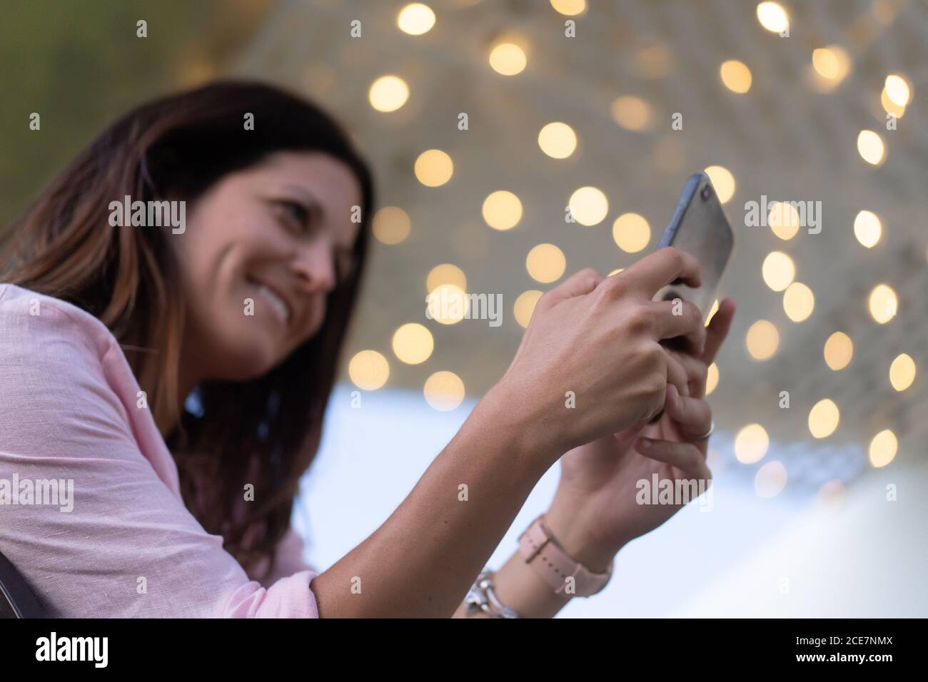 Side view low angle of content female taking photo on mobile phone ...