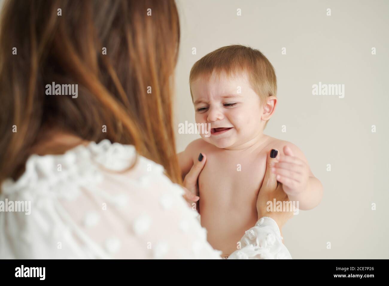 Crop unrecognizable mother holding and comforting tearful displeased ...