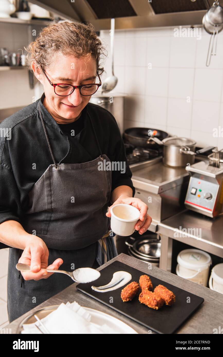 Female chef dressing a plate of croquette Stock Photo - Alamy
