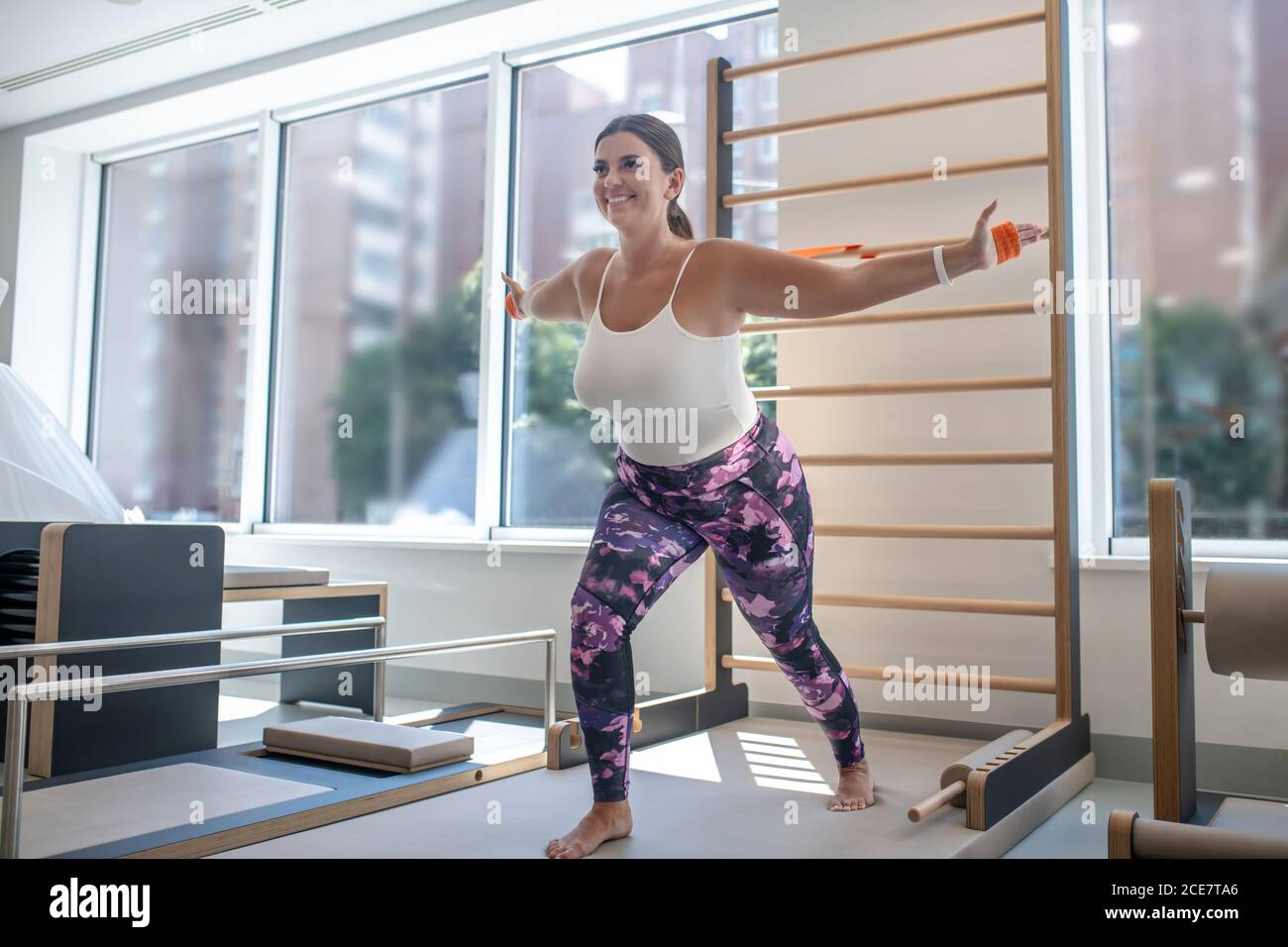 Brunette young plus size woman stretching the belts and feeling good ...