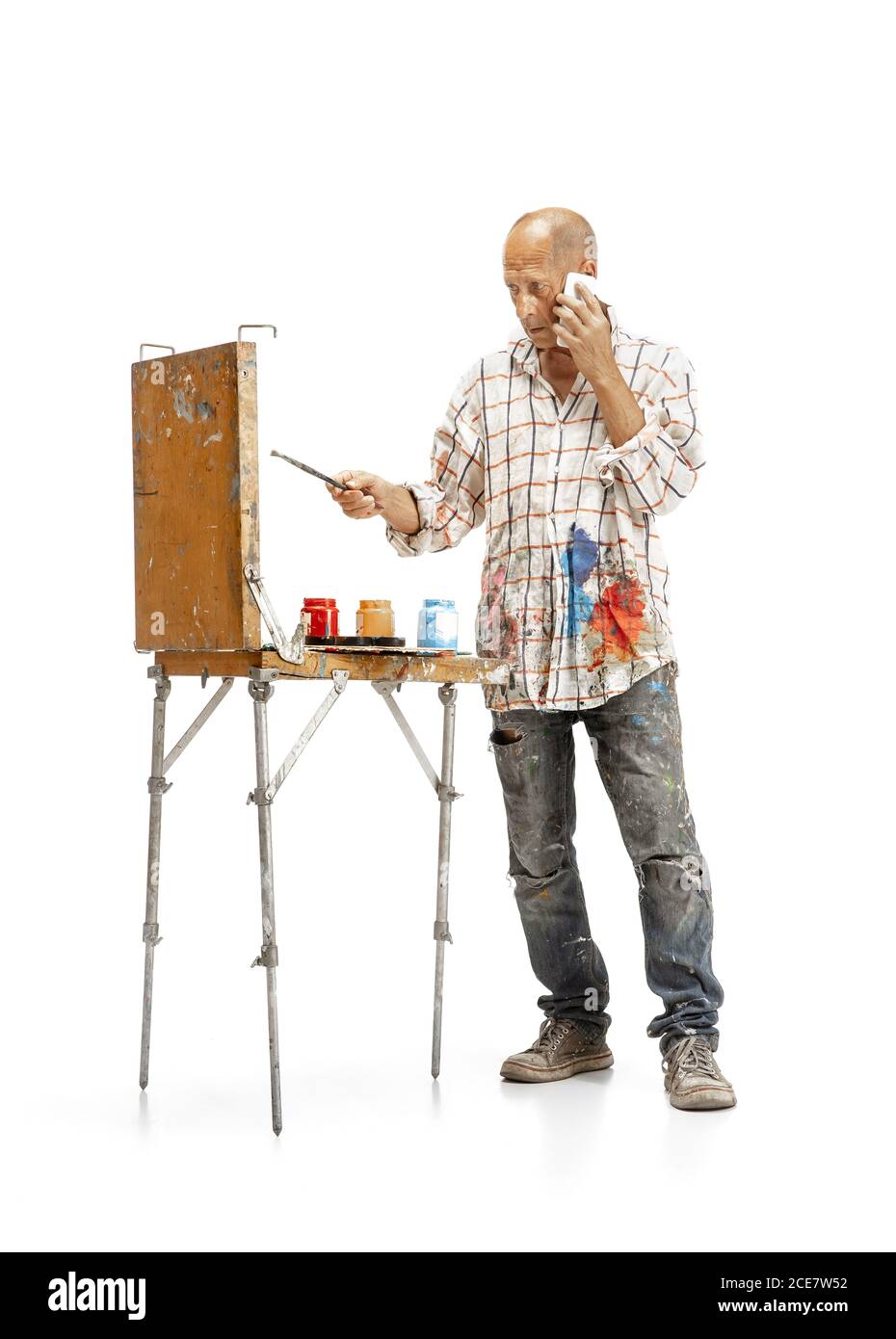 Talking phone. Male caucasian artist, painter at work on white studio ...