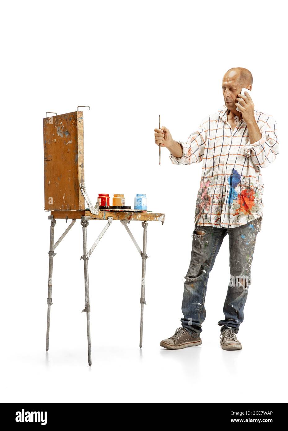Talking phone. Male caucasian artist, painter at work on white studio ...