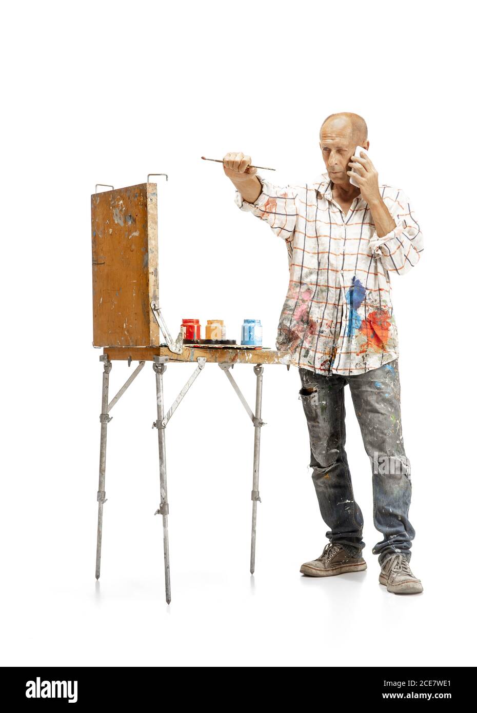 Talking phone. Male caucasian artist, painter at work on white studio ...