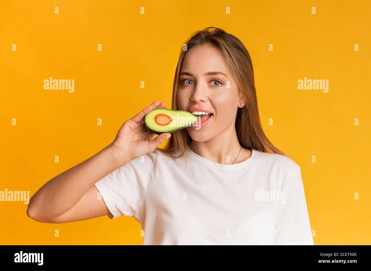 Beautiful Girl Eating Avocado Half And Posing Over Yellow Background ...
