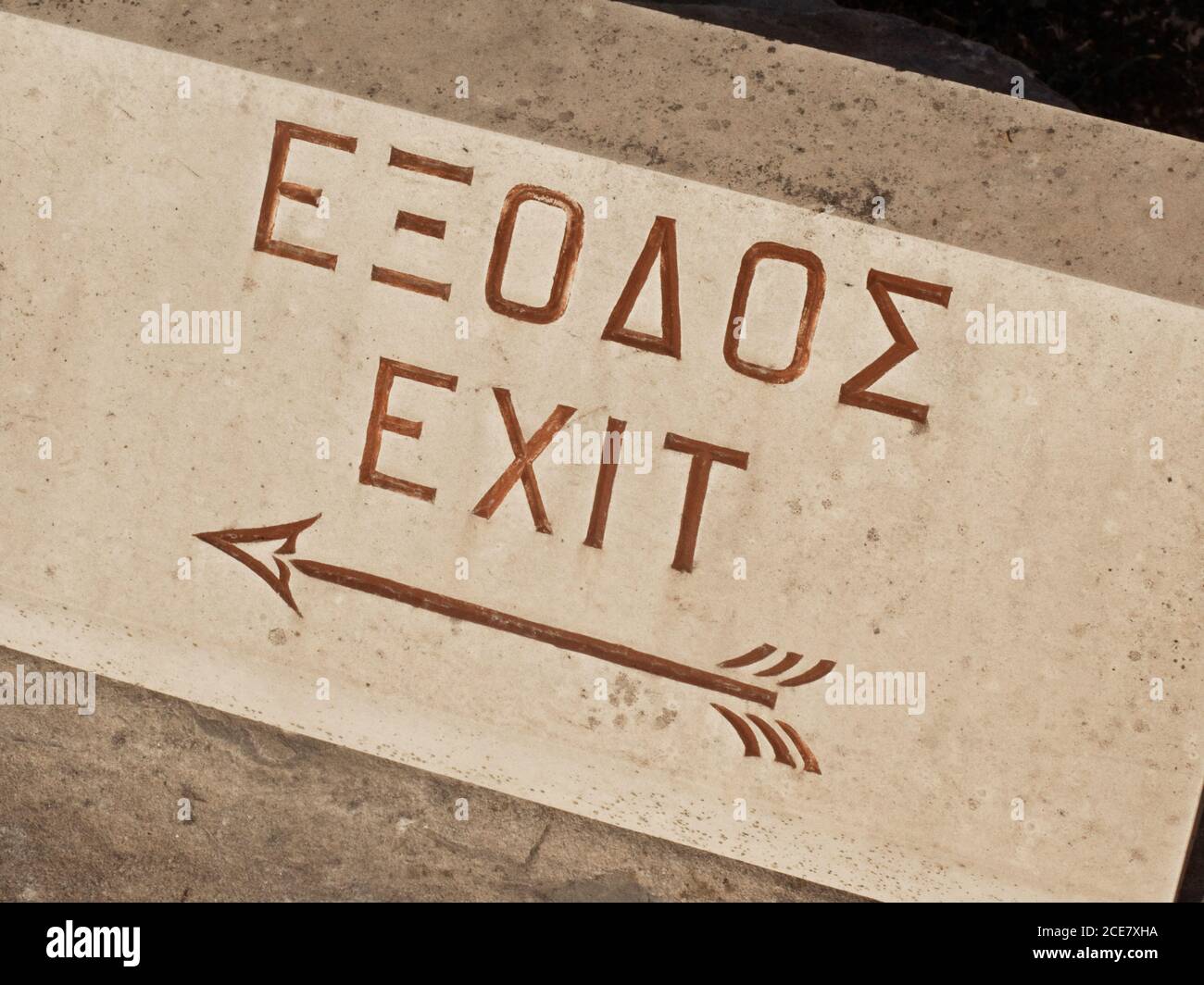 Light stone signboard with inscription exit in Greek and English ...