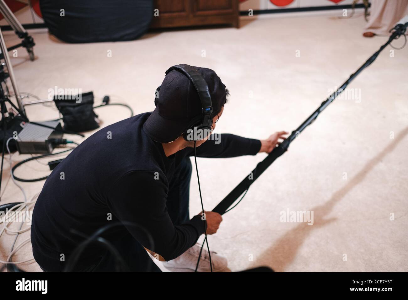 Back view faceless assistant crouched using professional shotgun ...