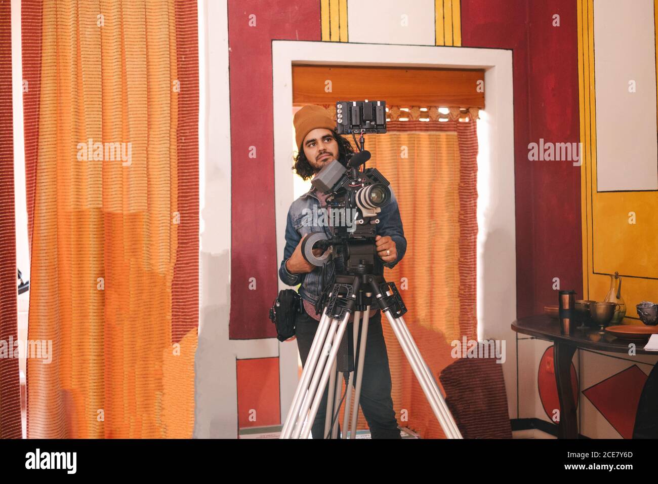 Concentrated male videographer standing behind professional video ...