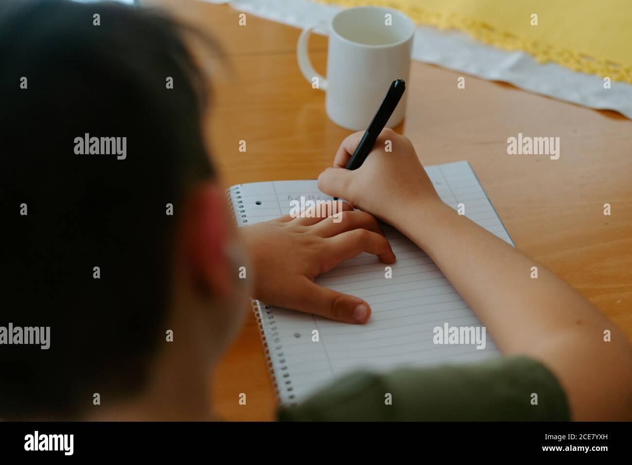 From above of crop anonymous child writing in spiral notebook while ...