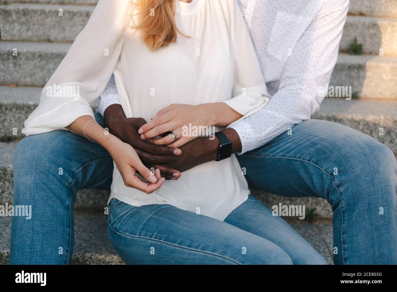 Crop faceless multiethnic couple bonding and holding hands together ...