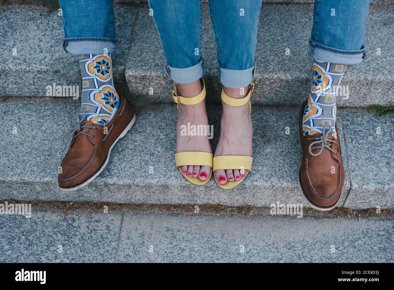 From above crop anonymous girlfriend in jeans sitting on street ...