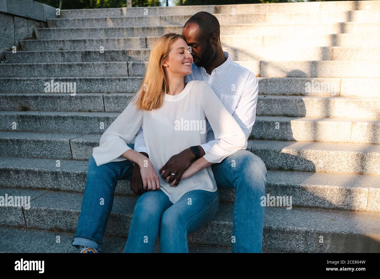 Content black boyfriend sitting on street stairs behind smiling ...