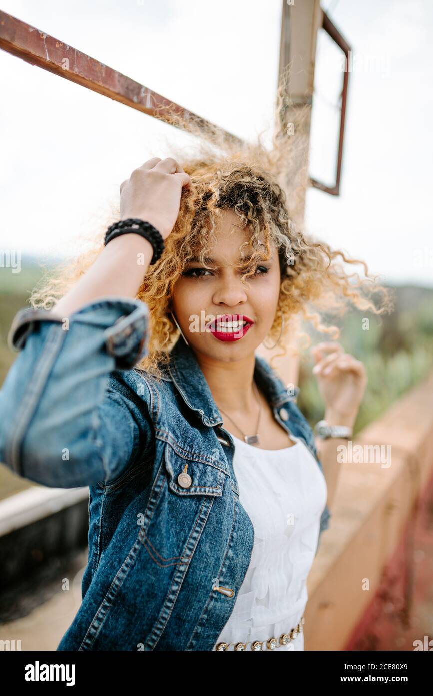 Content African American female in fashionable wear standing near metal ...