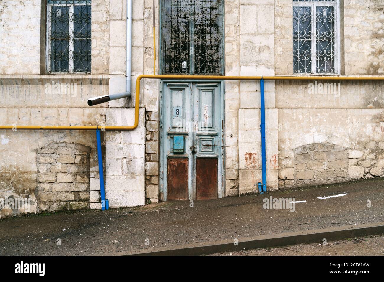 Facade of weathered stone building with wooden door and windows on ...