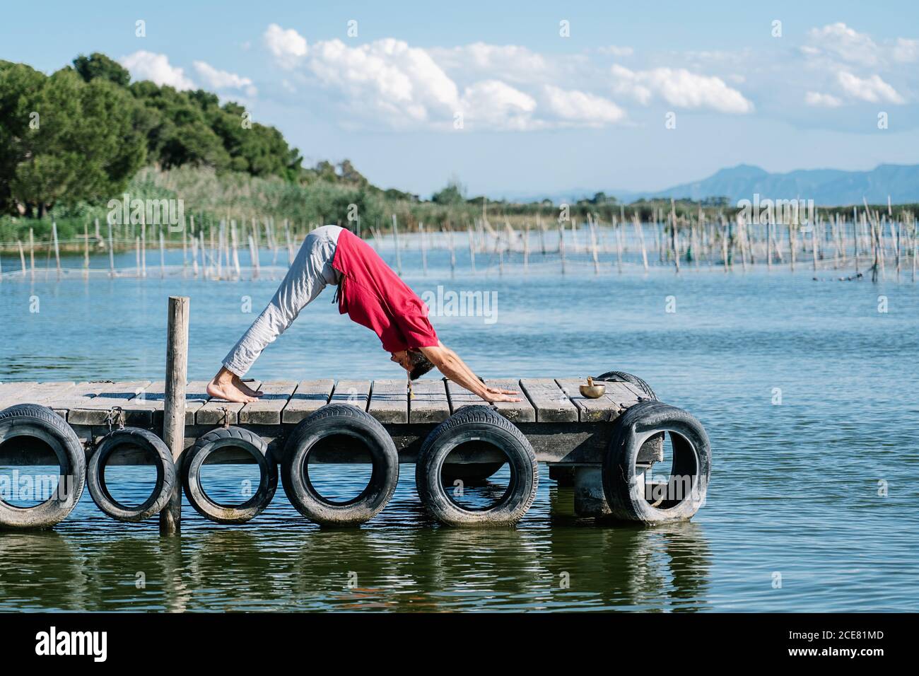 Full body of peaceful barefooted guy in casual wear performing yoga ...
