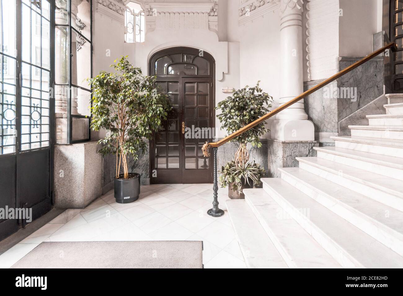 Large stair with wooden railing and classic columns with ornamental ...