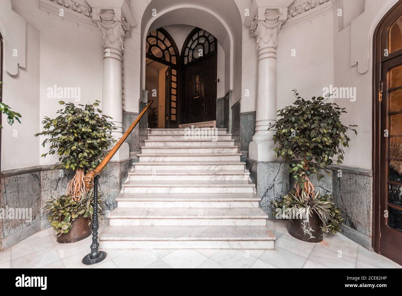 Large stair with wooden railing and classic columns with ornamental ...
