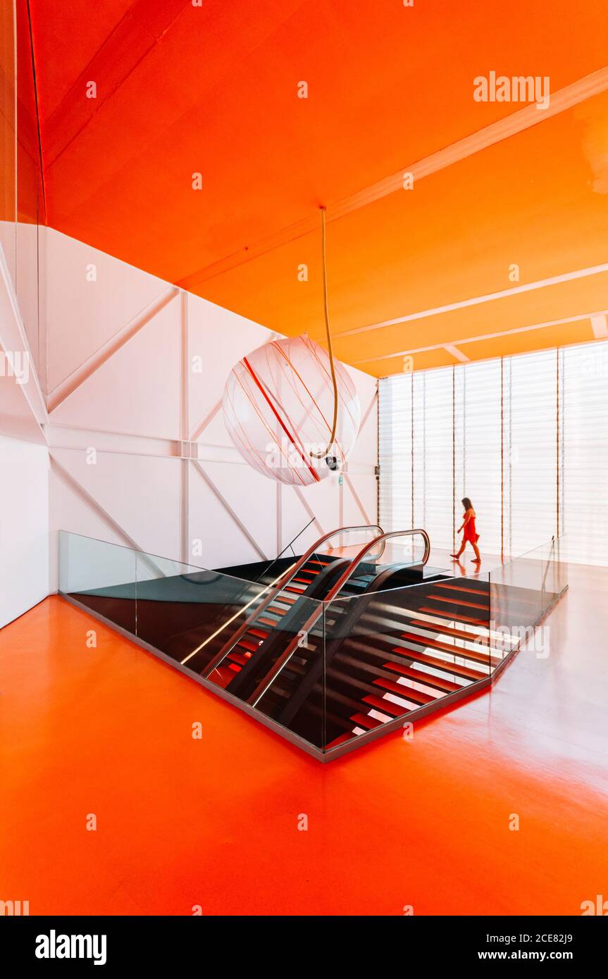 Side view of female walking along spacious passage with stairs and ...