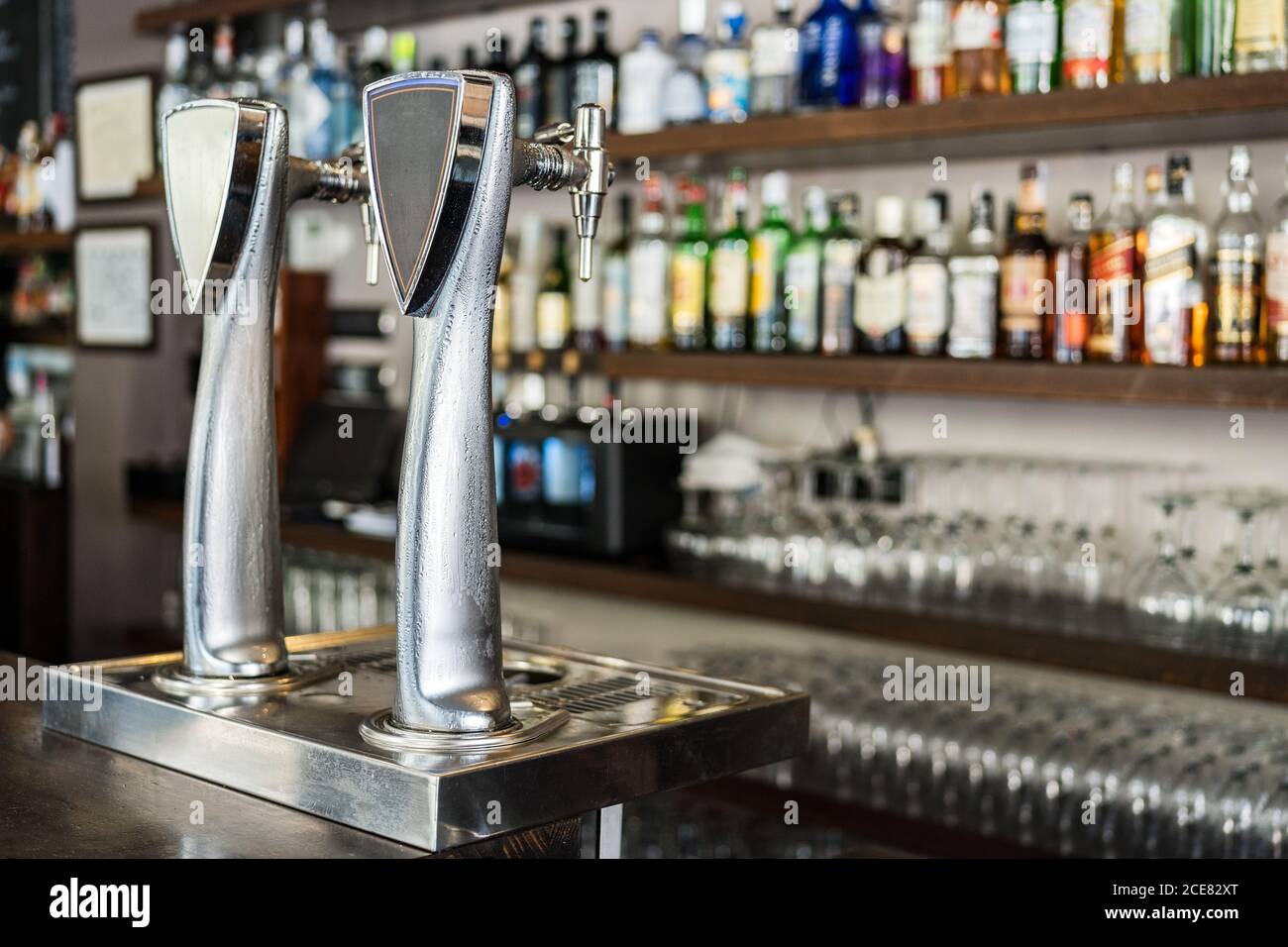 Metallic beer column placed on bar counter against shelves with ...