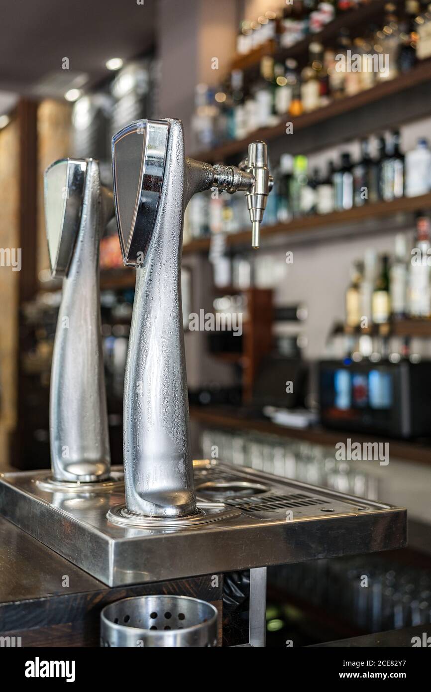 Metallic beer column placed on bar counter against shelves with ...
