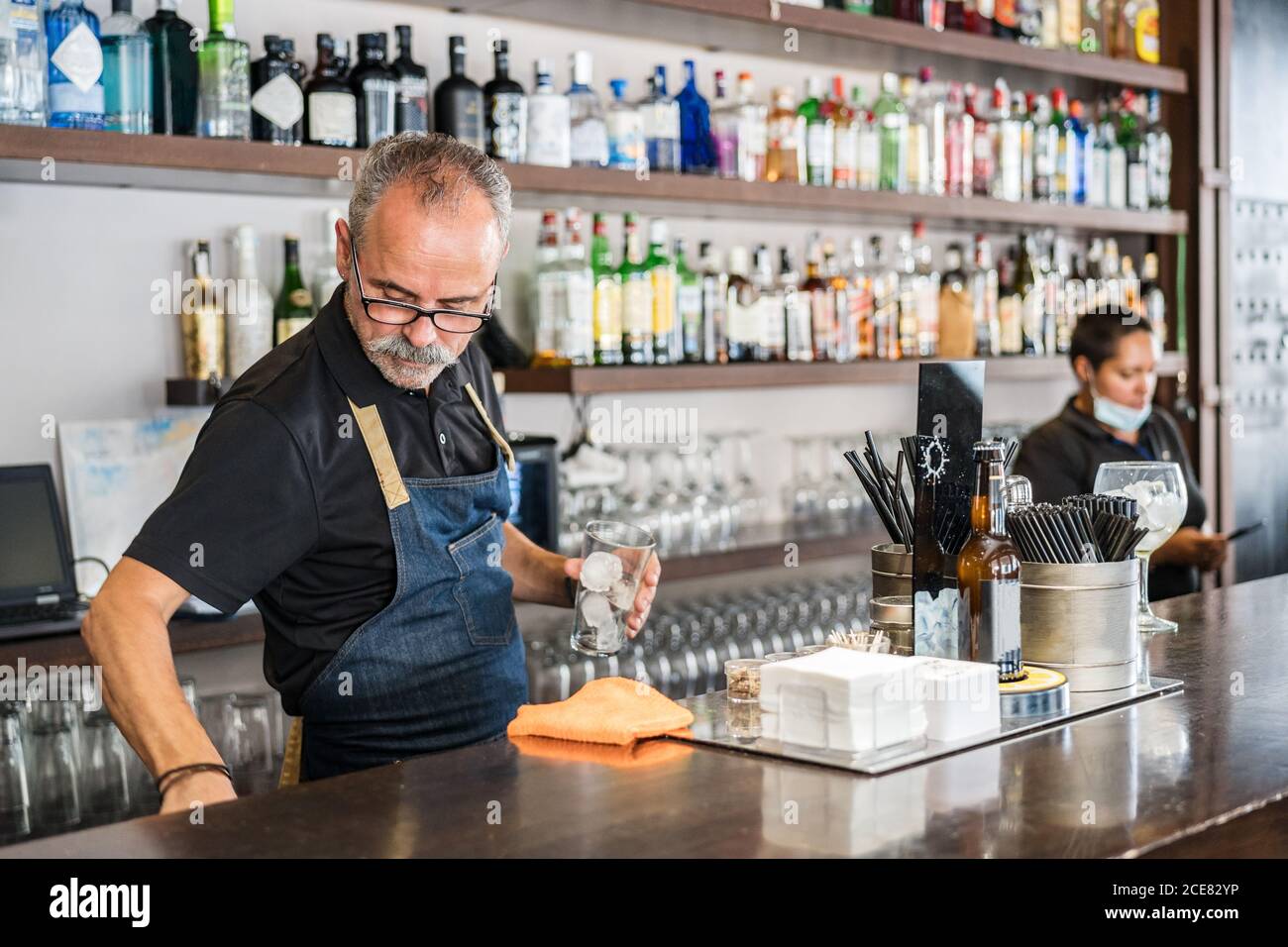 Side view of male and female bar coworkers making drinks during working ...