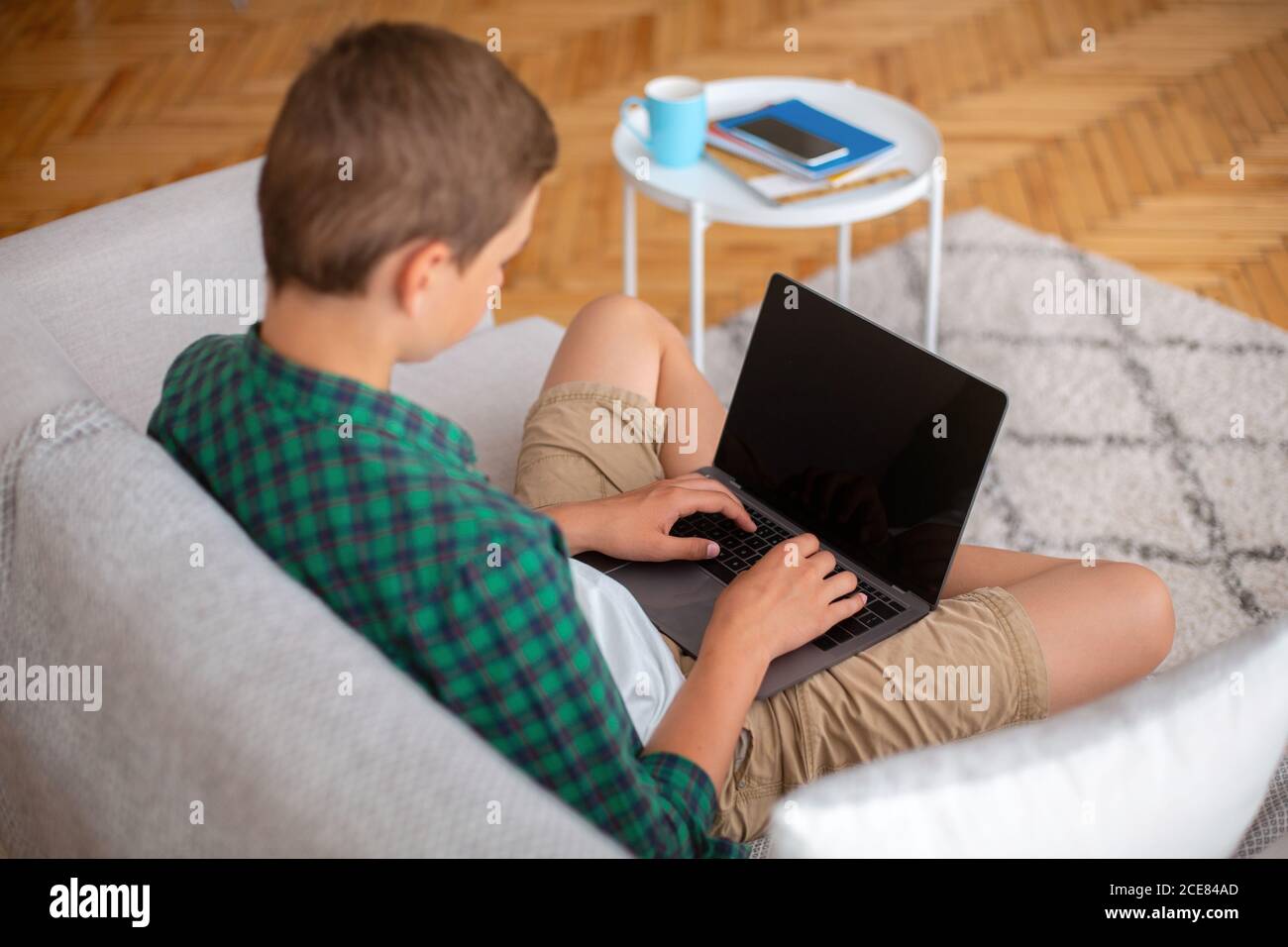 Teenager using laptop with blank screen, sitting at home Stock Photo ...