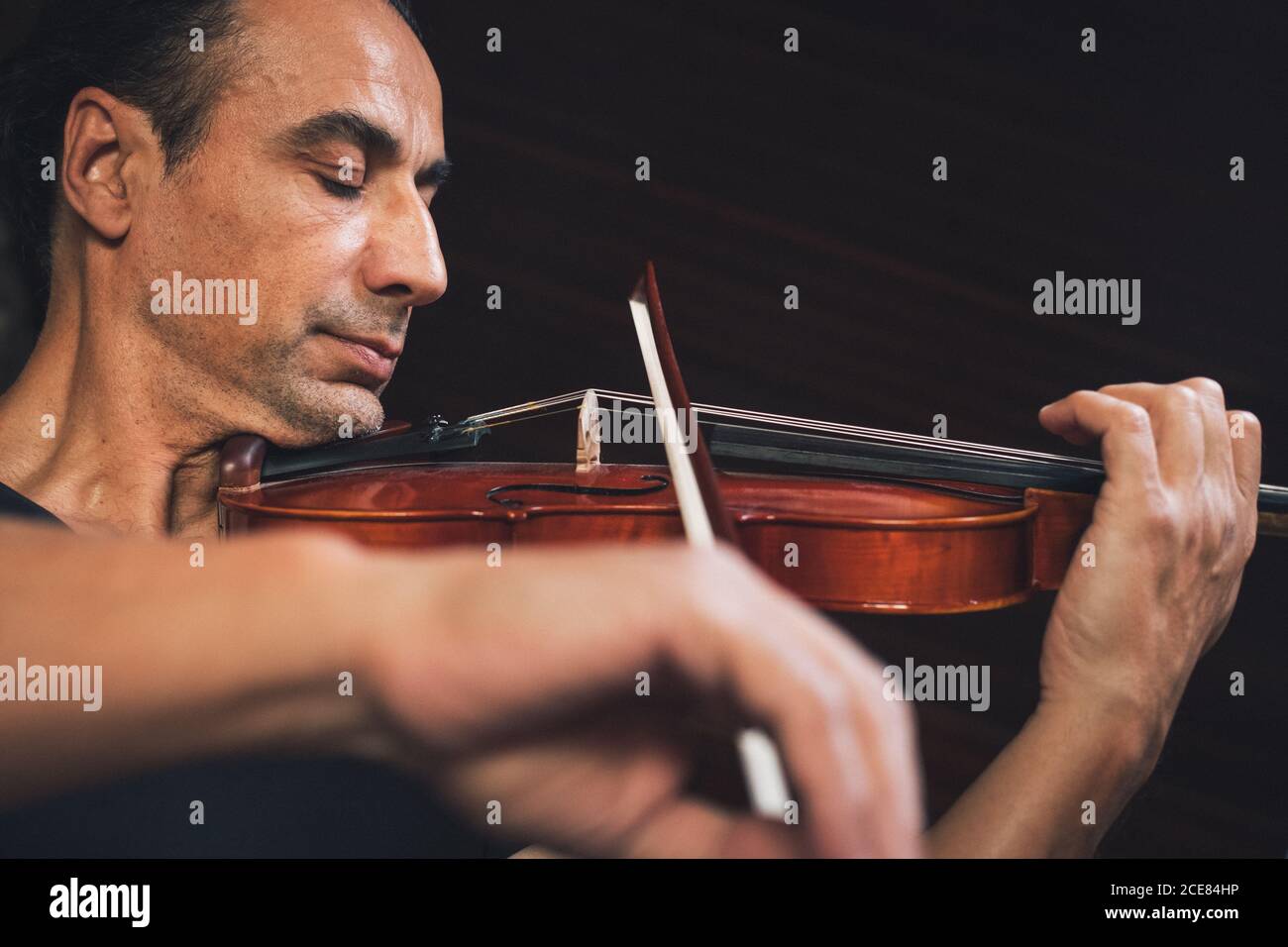 Talented Hispanic male violinist playing violin and looking at music ...