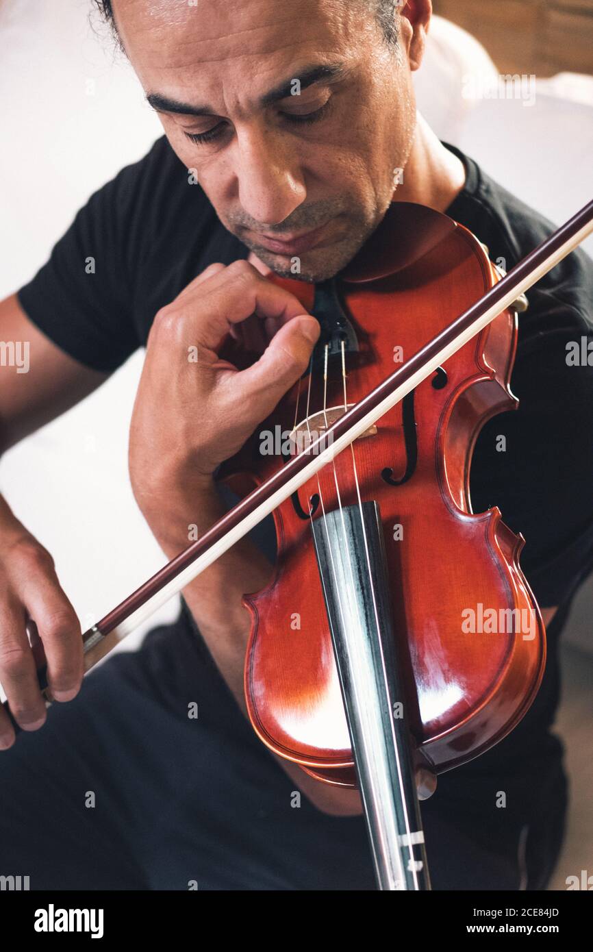 From above talented focused Hispanic male violinist playing violin ...