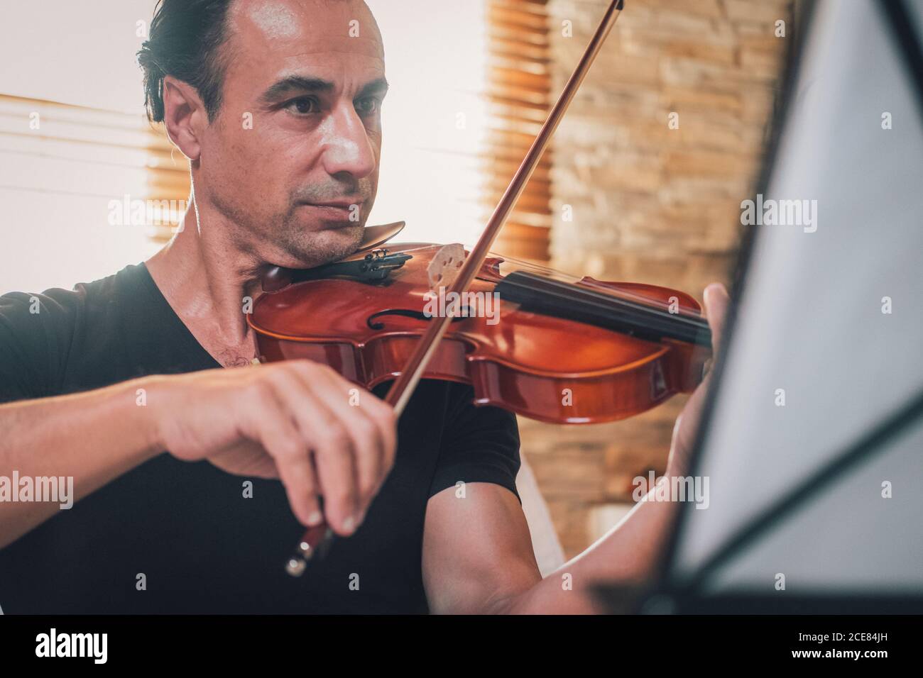 Talented Hispanic male violinist playing violin and looking at music ...