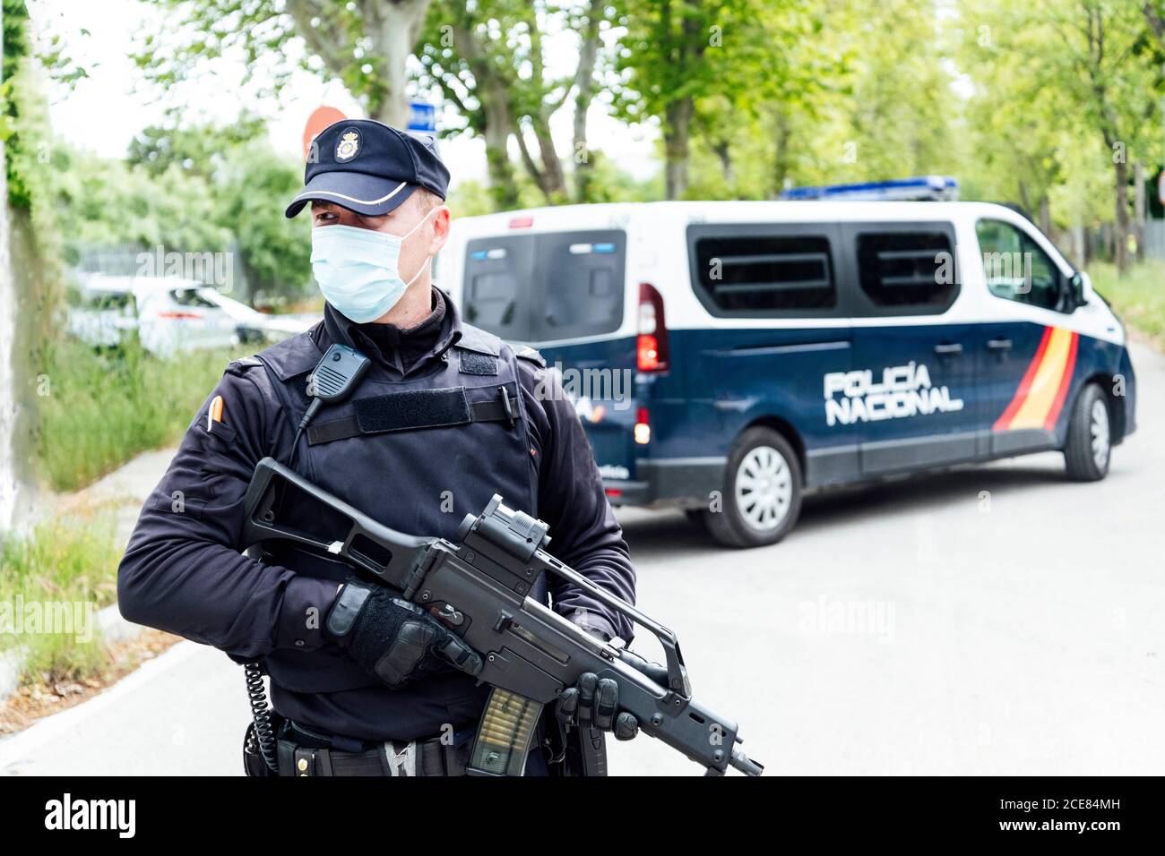Concentrated police officer in uniform and medical mask looking away ...