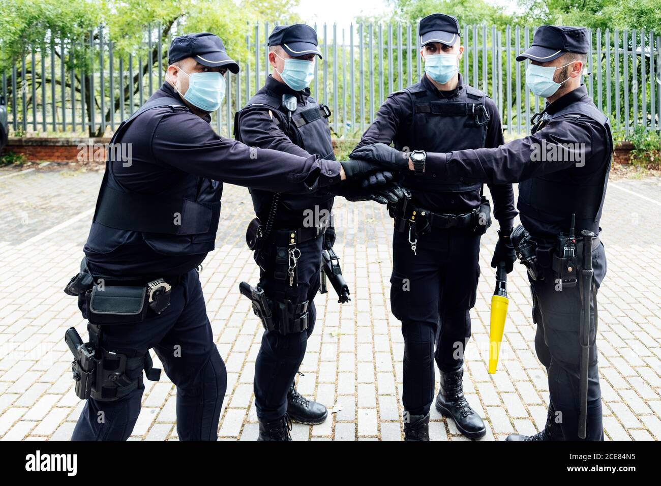Serious anonymous police officers in protective gears and medical masks ...