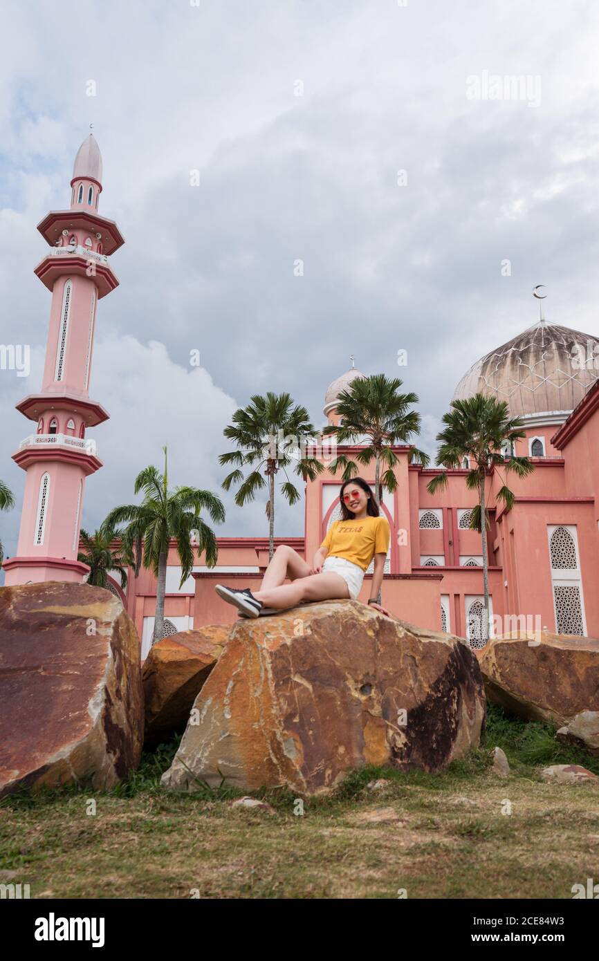Cheerful ethnic female tourist sitting in front of UMS Mosque in Kota ...